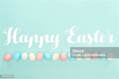 파스텔 그린 계란의 상단보기는 파란색에 고립 된 행복한 부활절 문자와 함께 행에 계란을 그린 0명에 대한 스톡 사진 및 기타 이미지 Istock