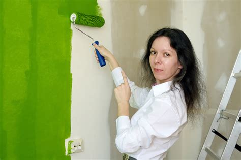 웃는 예쁜 젊은 여자의 초상화 흰색 셔츠 그림 녹색 인테리어 벽을 새 집에서 롤러와 그녀의 작품을 가리키는 Diy에 대한 스톡 사진 및 기타 이미지 Istock