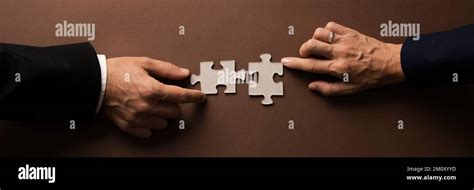 Wide View Image Of Businessman And Businesswoman Hands Joining Two Blank Matching Puzzle Pieces