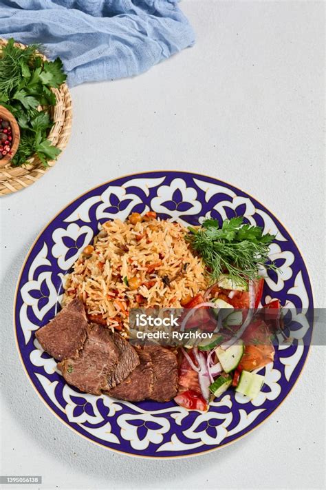 전통적인 우즈벡 음식 쇠고기와 함께 Plov 동양 요리 쌀 고기 및 향신료가있는 필라프 전통적인 우즈벡 접시에 쇠고기를 곁들인 플로브 필라프와 동양 세라믹 플레이트의 구성