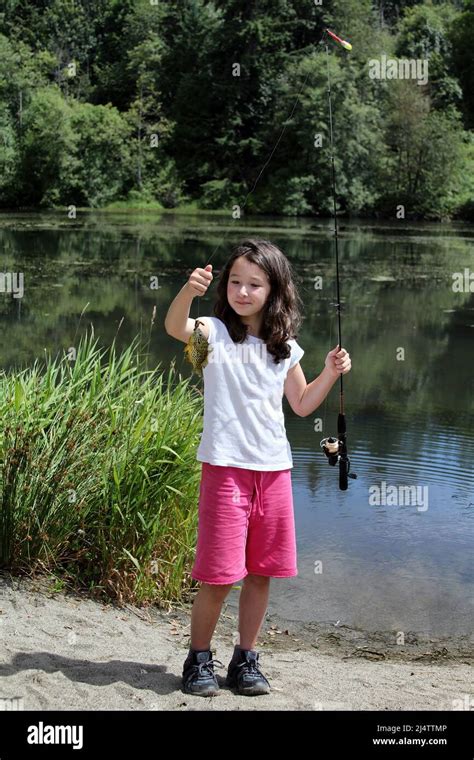 Young Girl Admiring Her Sunfish She Caught While Fishing In A Small