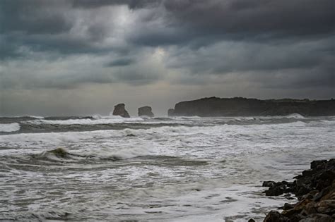 헨다예 해변 프랑스 바스크 컨트리 폭풍을 위협하는 구름으로 가득 찬 날 해안을 배경으로 두 개의 쌍둥이 바위 레 두 주메오 전경에 진흙 바다 휴식의 큰 파도가있는 산책로의