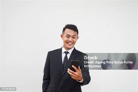초상화는 웃는 얼굴에 행복해하는 젊은 아시아 사업가 주먹 펌프 손은 하얀 배경에 고립된 전화로 좋은 소식을 본다 25 29세에 대한 스톡 사진 및 기타 이미지 Istock