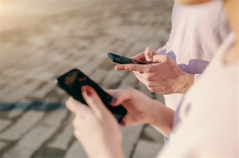 Premium Photo Close Up Of Man And Woman Using Smart Phones While Standing Side By Side Outdoors