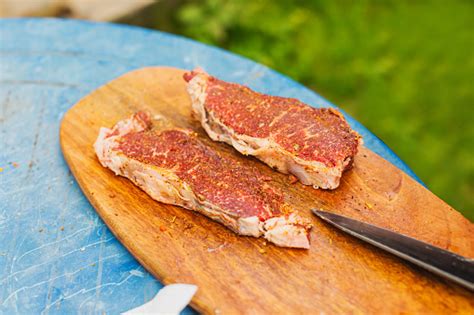 신선한 쇠고기 스트리플로인 스테이크 야외 에서 체험할 수 있습니다 뒤뜰에서 저녁 식사 나무 판에 붉은 고기 음식 준비 과정 송아지 고기 맛있는 간식 야외 식사 소금과 계절