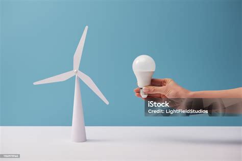 파란색 배경에 풍차 모델과 흰색 테이블 위에 전구를 들고 여자의 자른 보기 발전기에 대한 스톡 사진 및 기타 이미지 발전기 부분의 사람들 Istock