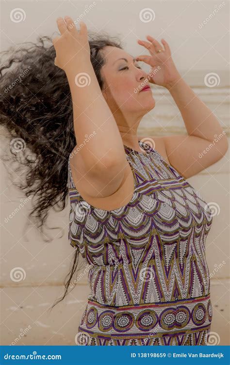 image of a woman on the beach with long black hair tousled by the wind stock image image of