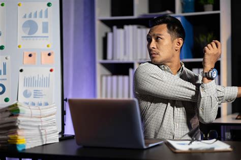 과로로 고통받는 남자는 야간 사무실에서 초과 근무를하면서 스트레칭과 휴식을 취하고 있습니다 남자에 대한 스톡 사진 및 기타 이미지 Istock