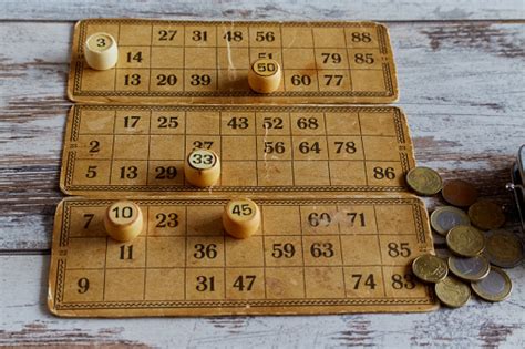 근처에 유로 센트 동전이있는 나무 테이블에 노랗게 변한 빈티지 빙고 카드 동전과 함께 낡은 테이블에 오래된 빙고 게임 카드 전통적인 가정 빙고 게임 돈을 위해 빙고 게임