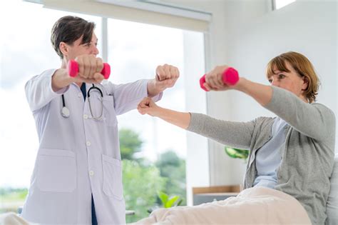 백인 노인 환자 여성은 침대에 앉아서 병원에서 치료 후 운동하기 위해 덤벨을 들어 올립니다 의사와 함께 운동 의료 의료 및 물리 치료사 보험 개념 2명에 대한 스톡 사진 및