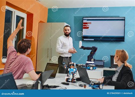 A Group Of Colleagues Working Together In A Robotics Laboratory Focusing On The Intricate