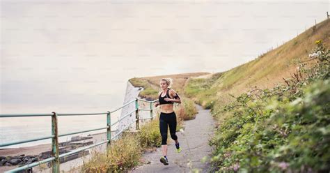 이어폰을 낀 젊은 스포티한 여성 러너는 자연 속에서 바다를 달리며 음악을 듣는다 사진 Unsplash의 슬로바키아 이미지