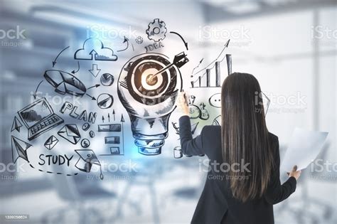 젊은 매력적인 유럽 사업가의 백 뷰는 흐릿한 사무실 인테리어 배경에 창조적 인 손으로 그린 비즈니스 스케치를 그립니다 교육