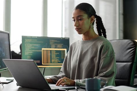 Middle Eastern Female Programmer Using Laptop Sitting At Workstation In Office Stock Image