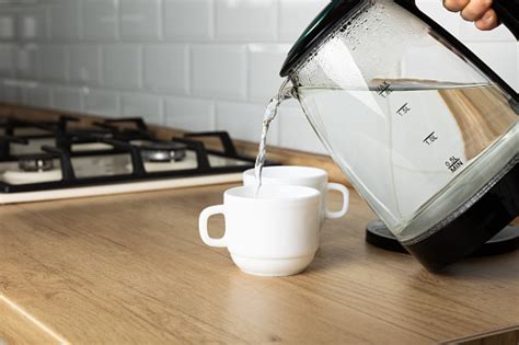 주방의 나무 테이블에 있는 현대적인 전기 투명 주전자 물을 끓이고 차를 만들기위한 주전자 뜨거운 음료를 만들기위한 가전 제품 복사 공간 텍스트를 위한 장소입니다 가정 생활에