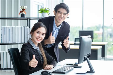 사무실 배경회의에서 나무 테이블에 컴퓨터와 아이디어와 함께 일하는 긍정적 인 성인 비즈니스에 대해 논의하는 엄지 손가락을 보여주는 사업가와 사업가 파트너의 행복 20 29