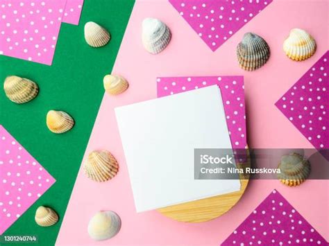 둥근 나무 베이스에 추상적 인 평탄색 사각형 노트 시트 분홍색 녹색 대각선 종이 배경 라일락 종이의 모서리 둘레에 흰색 물방울