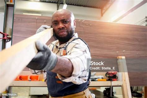 중년의 아프리카 목수의 초상화는 앞치마를 두르고 나무 판자를 측정하고 조준하고 노동자는 목공 작업장에서 목재 가구를 만들고 목공 작업장에서 일하는 장인 40 44세에 대한