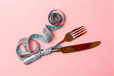 당신의 디자인을위한 빈 공간과 분홍색 배경에 말린 측정 테이프 포크와 칼의 구성 과체중 개념 0명에 대한 스톡 사진 및 기타 이미지 Istock