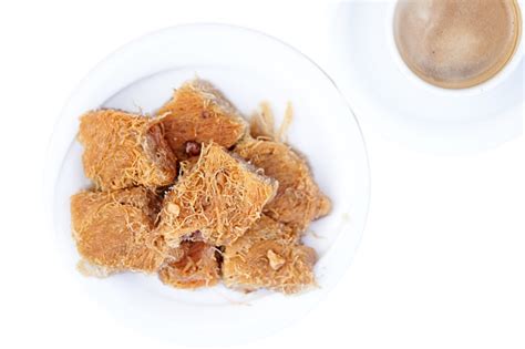 커피 한 잔과 함께 흰색 접시에 갓 만든 아라비아 바클라바를 식욕을 돋우고 있습니다 위에서 볼 수 있습니다 전통 동양 과자 음식 격리된 이미지입니다 텍스트의 장소 갈색에