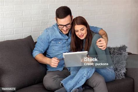 젊은 부부는 방에서 온라인 쇼핑에 시간을 보내는 손에 태블릿과 신용 카드와 소파에 앉아 Brand Name Mobile Payment에 대한 스톡 사진 및 기타 이미지