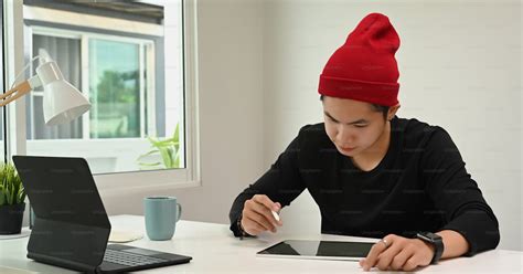 빨간 양모 모자 손에 그래픽 디자이너 또는 사진 작가가 디지타이저에 스타일러스 펜 드로잉을 들고 있습니다 사진 Unsplash의 테이블 이미지