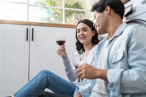아시아의 젊은 신혼 부부는 집에서 부엌에서 함께 시간을 보낸다 매력적인 낭만적 인 남자와 여자는 가족 관계 생활과 새 집으로 이사하는 것을 축하하기 위해 와인을 마신다