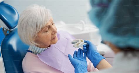 수술의자에 앉은 은퇴한 여성에게 실리콘에서 탄력 있는 치아 인상을 제공하는 치과 의사 사진 Unsplash의 실내 이미지