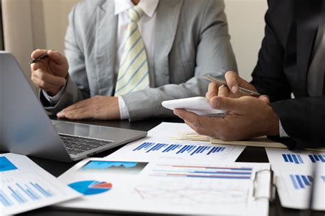 재무 고문은 사업가와 함께 일하면서 사무실 책상에서 데이터를 계산하고 분석합니다 2명에 대한 스톡 사진 및 기타 이미지 2명 Earnings Before