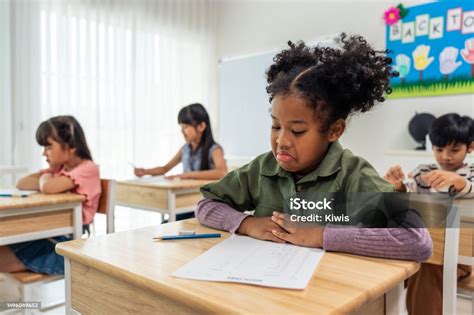 초등학교 교실에서 시험을 보는 아프리카계 미국인 학생 어린 사랑스러운 아이들이 식탁에 앉아 혼란스럽고 긴장하면서 유치원에서 선생님과 함께 수업 과목을 배웁니다 교실에 대한