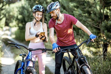 숲 길에서 스마트폰을 들고 자전거를 타는 남녀 사이클리스트 두발자전거에 대한 스톡 사진 및 기타 이미지 두발자전거 커플 휴대전화 Istock