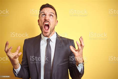 노란 고립 된 배경을 통해 젊은 잘 생긴 사업가 미친 미친 미친 소리와 공격적인 표정과 팔을 제기 고함 좌절 개념입니다 남자 사업가에 대한 스톡 사진 및 기타 이미지