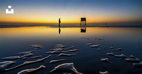 해질녘 물 한가운데서 바위 위에 서 있는 사람 사진 Unsplash의 무료 바닷가 이미지