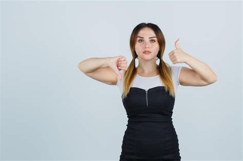 Молодая женщина показывает палец вверх и вниз Бесплатно Фото