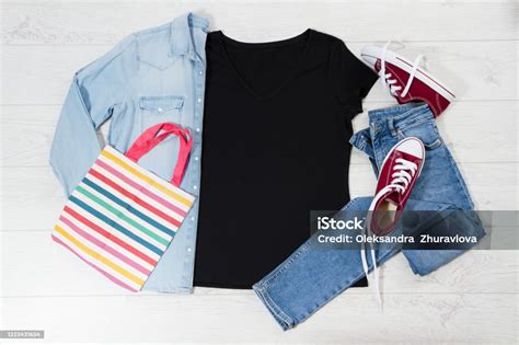 T 셔츠 블랙과 스 니 커 즈 여름 액세서리와 T 셔츠 목업 플랫 레이 가방 청바지와 나무 바닥 배경에 운동화 공간을 복사합니다 템플릿 빈 캔버스입니다 전면 상단 뷰입니다