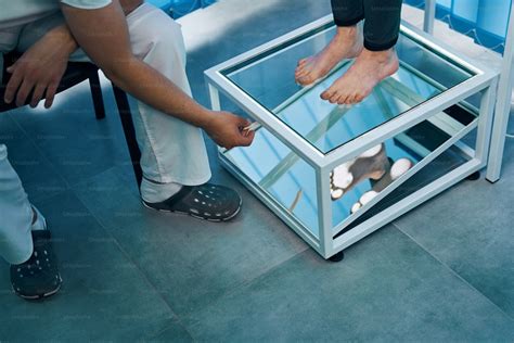 사무실에서 치료사와 함께 플랜토스코피로 평발에 대한 소녀 발 근접 검사 의료실에서 플랜토스코프 장치의 플랫폼에 있는 여자 외반 발 검사 건강한 라이프 스타일 약 사진