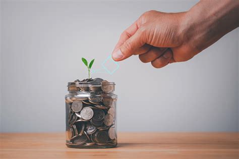 금융 및 비즈니스 배경을 위해 유리 항아리가 있는 전체 돈 동전에 손으로 물을주고 식물은 위에 자랍니다 저축 및 계좌 금융 은행 사업 아이디어 투자 자금 및이자