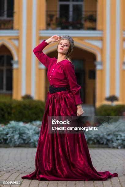 실버 티아라가 빨간 드레스를 입고 올드 빌딩을 상대로 손을 들어 포즈를 취하는 자신감 넘치는 백인 소녀 세로 이미지 컴포지션