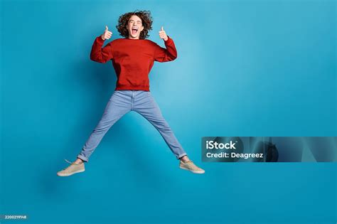 잘생긴 자신감 있는 남자가 빨간 스웨터를 입고 높이 점프하는 엄지 손가락을 보여주는 Emtpy 공간 고립 된 파란색 배경의 전체 길이 사진 20 24세에 대한 스톡 사진 및