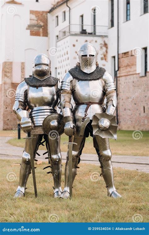 Two Knights In Ancient Metal Armor Stand At The Stone Wall Of The