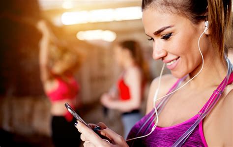 젊은 매력적인 피트 니스 모델 외부 운동 전에 스마트 폰 Charching 긍정적인 에너지에 듣는 음악 태양은 빛나고 고 친구 훈련에 대 한 준비 뒤에 Mp3 플레이어에