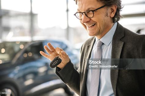 남성 수석 자동차 판매자 그의 손에 새 차의 열쇠를 들고 이빨 미소를 가지고 고객을보고 자동차 대리점에서 실내 50 59세에 대한 스톡 사진 및 기타 이미지 Istock