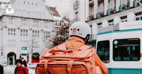 주황색 재킷과 검은 바지를 입은 남자가 낮에 보도를 걷고 있는 흰색 헬멧을 쓰고 있다 사진 Unsplash의 무료 배달원 이미지