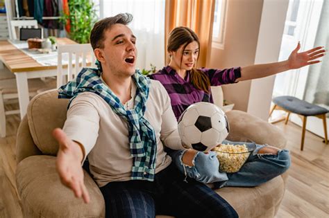 두 사람 커플 남자와 여자 친구와 여자 친구 또는 남편과 아내는 집에서 소파에 앉아 축구 축구 경기를 보며 복사 공간 긴장된 기대와 서스펜스를 응원합니다 아내에 대한 스톡