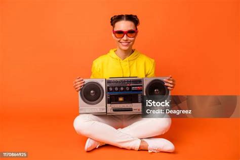 주황색 배경 위에 고립 된 안경 안경 노란색 스웨터를 입고 웃는 붐 박스를 들고있는 매력적인 여성의 초상화 갈색 머리에 대한 스톡 사진 및 기타 이미지 Istock