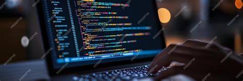 Developer39s Hands Working On A Laptop With Multiple Lines Of Code On A Black Screen In A