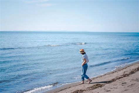 푸른 바다의 모래 해변을 따라 걷는 모자를 쓴 젊은 행복한 여자 여름 방학 및 여행 걷기에 대한 스톡 사진 및 기타 이미지 걷기 관광 관광 리조트 Istock
