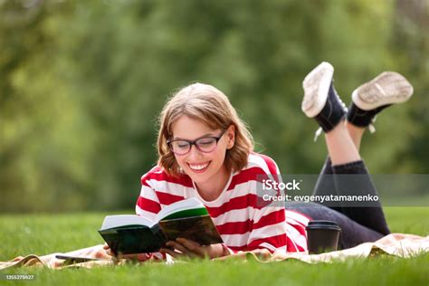 오픈 북과 도시 공원에서 외부 녹색 잔디에 누워 매력적인 미소와 안경에 사랑스러운 소녀 젊은 여자에 대한 스톡 사진 및 기타 이미지 젊은 여자 안경 야외 Istock