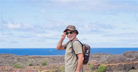 배낭과 모자를 쓴 행복한 활동적인 노인이 야외에서 하이킹을 하며 카메라를 바라보며 웃고 있다 은퇴와 건강한 생활 방식을 즐기는 노인 푸른 바다와 하늘을 배경으로 사진