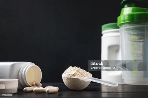 유청 또는 콩 단백질 파우더 한 스쿱 아미노산 비타민 및 크레아틴의 흰색 캡슐 보디 빌딩 식품 보조제 스포츠 영양 어두운 나무